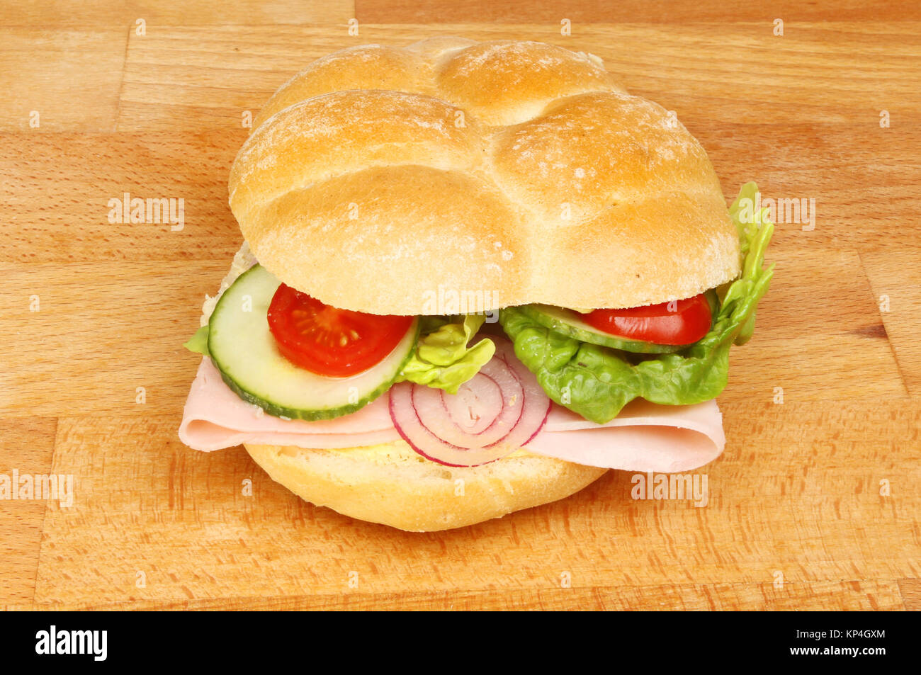 Ham and salad in a plaited bread roll on a wooden chopping board Stock ...