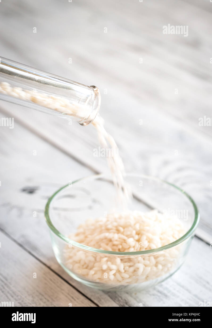 Pouring rice into glass bowl Stock Photo - Alamy