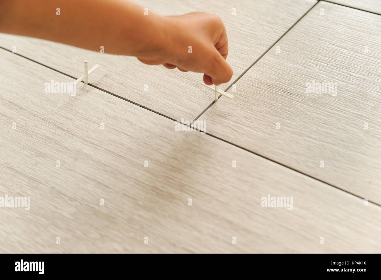 Laying Ceramic Tiles. Workers hand sets, plastic crosses between the ...