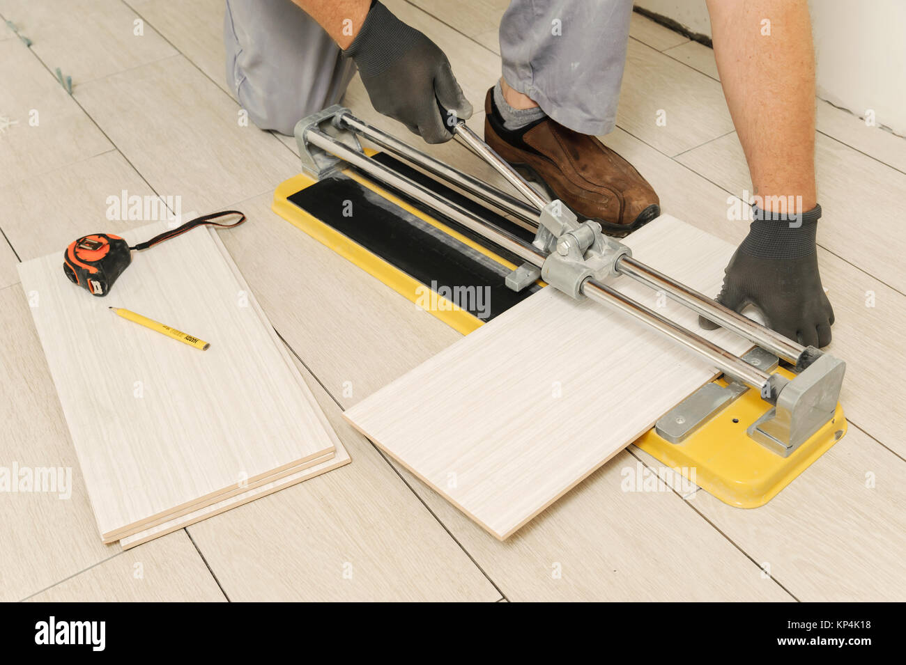 Laying Ceramic Tiles. Tiler cuts tile manual cutter Stock Photo - Alamy