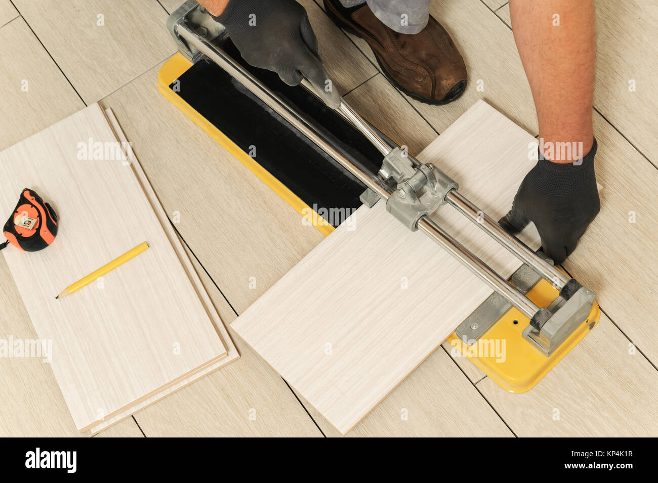 Laying Ceramic Tiles. Tiler cuts tile manual cutter Stock Photo - Alamy