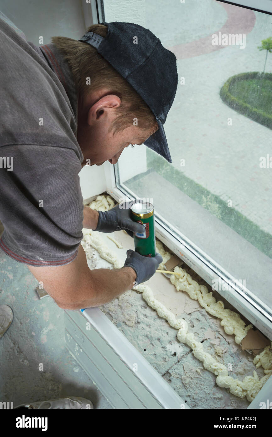 The worker installs a plastic sill using polyurethane foam Stock Photo ...