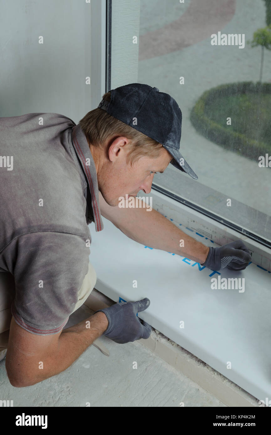 Worker installs plastic sill Stock Photo - Alamy