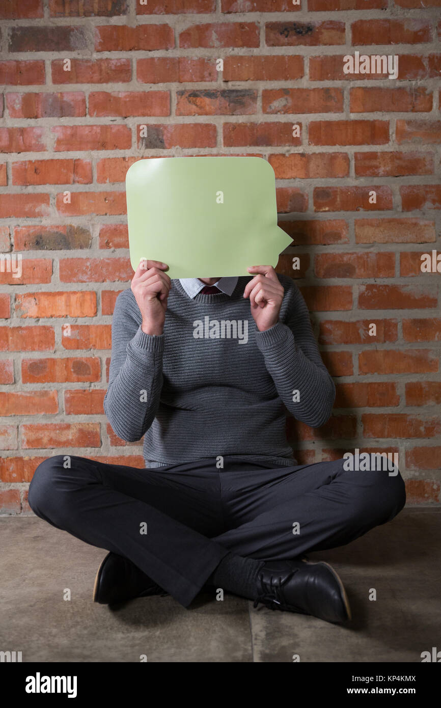 Male executive hiding his face with speech bubble in office Stock Photo ...
