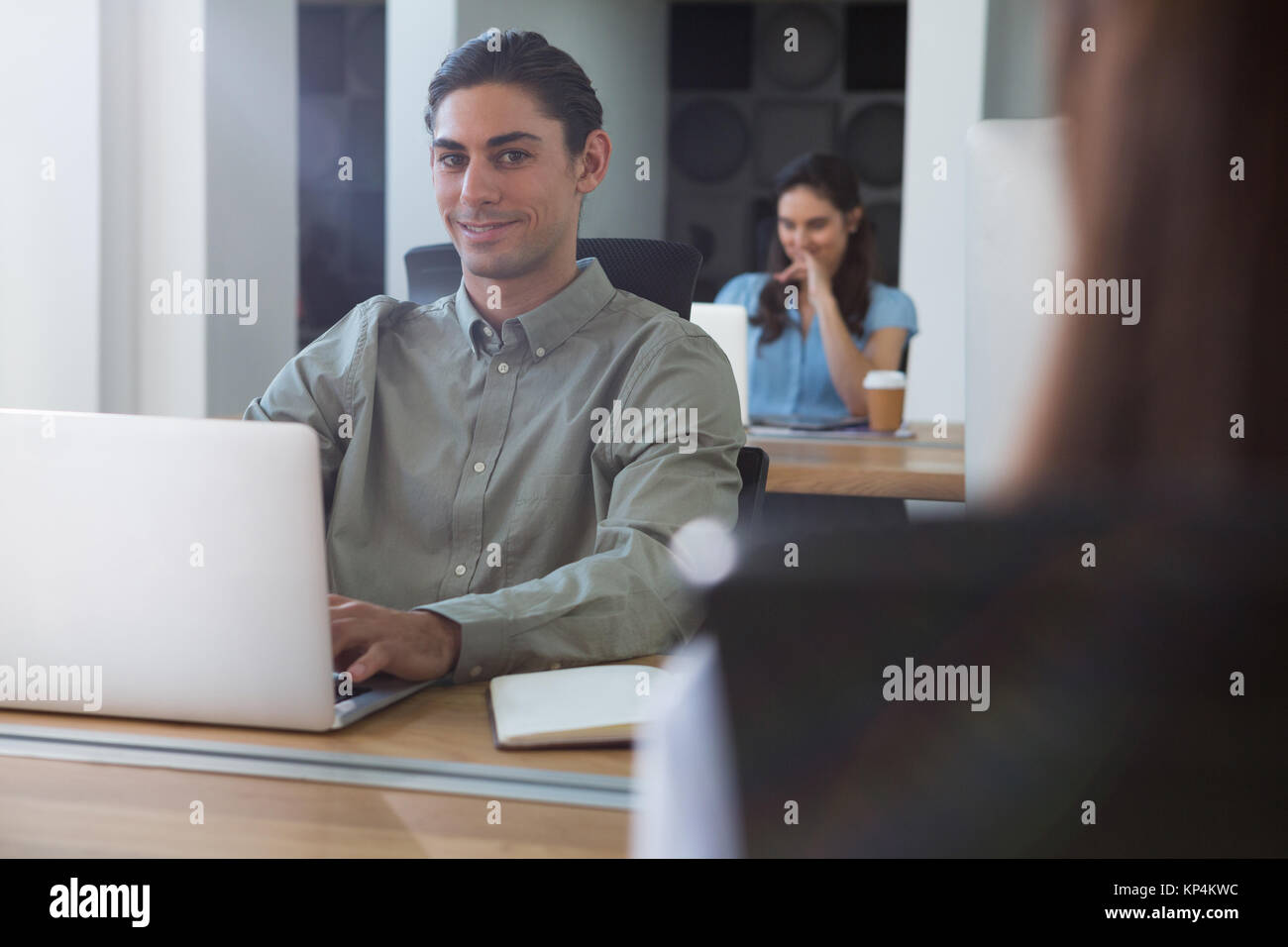 Smiling male executive working on laptop while looking at camera Stock ...