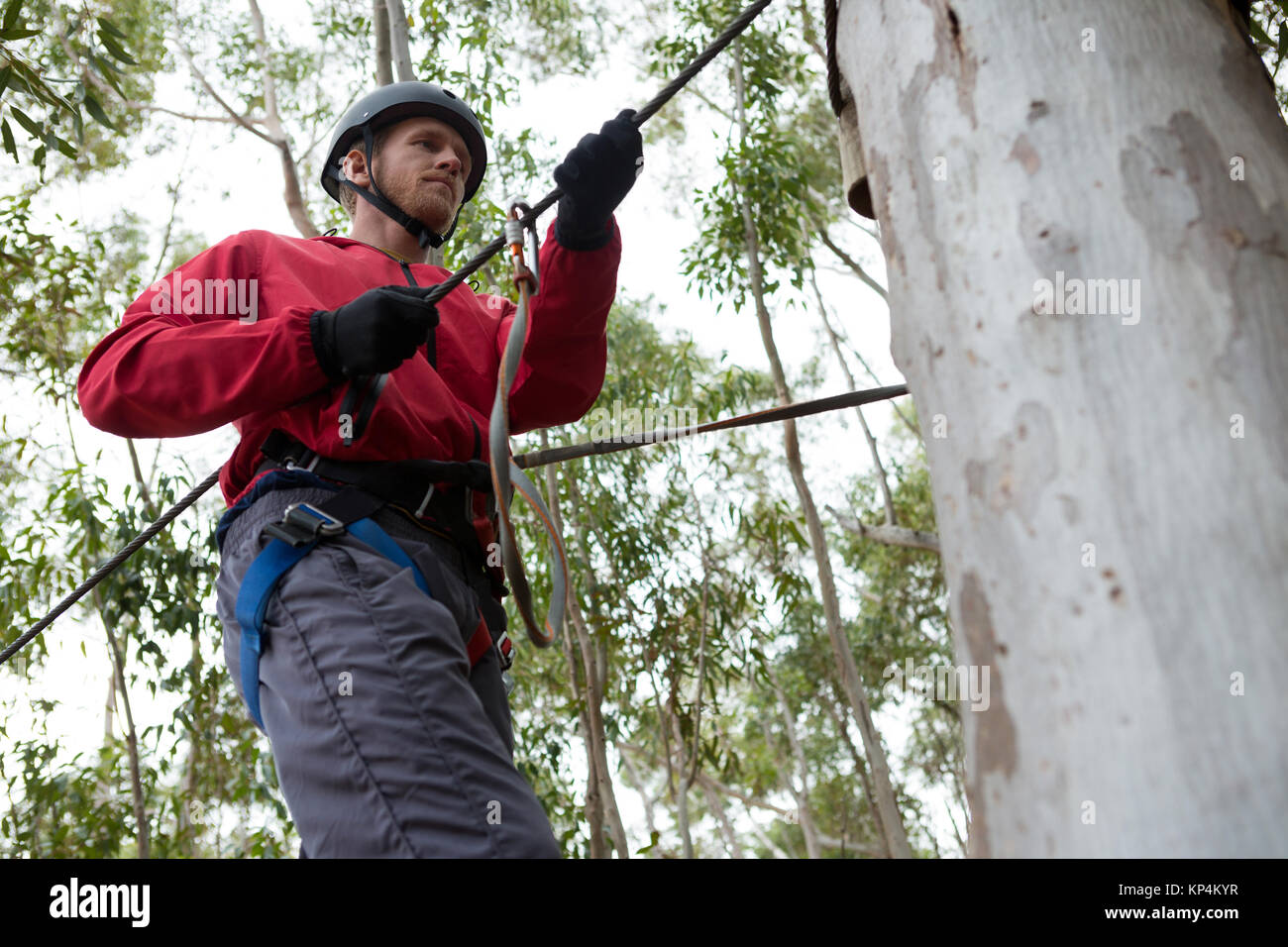 Close-up of young man wearing safety helmet crossing zip line in the ...