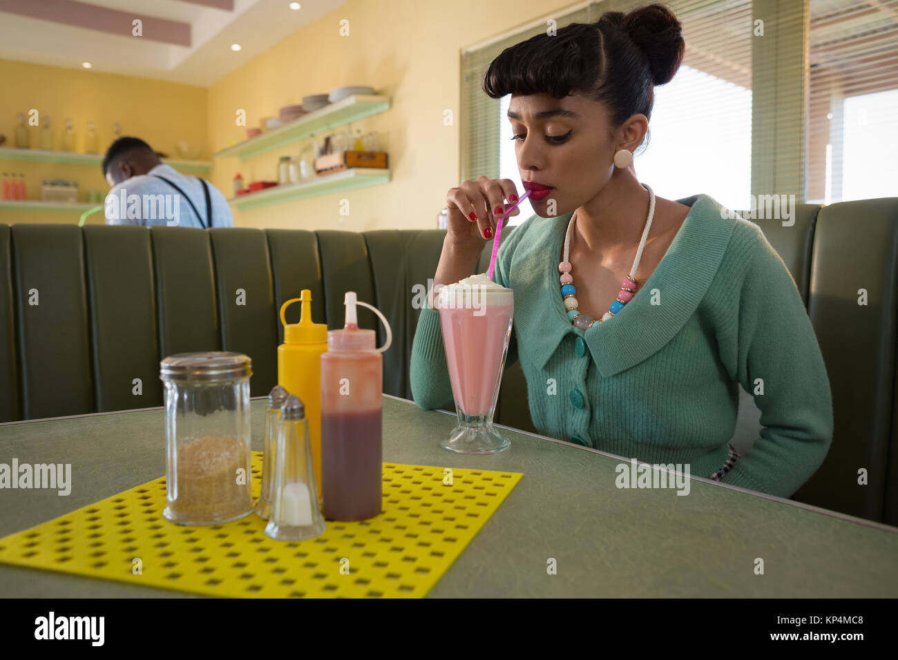 Young woman having milkshake at restaurant Stock Photo - Alamy