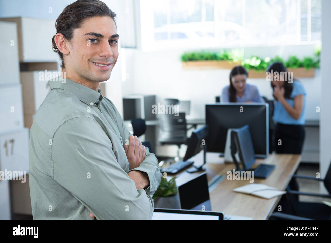 Smiling male executive looking at camera with folded hands in the ...