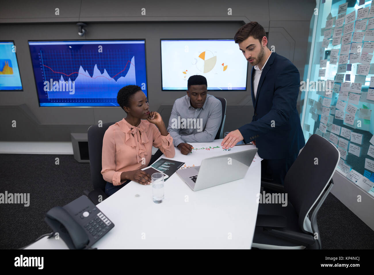 Male and female executives discussing over graph in boardroom Stock ...