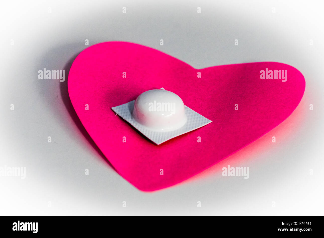 Drug pill on pink heart Stock Photo - Alamy