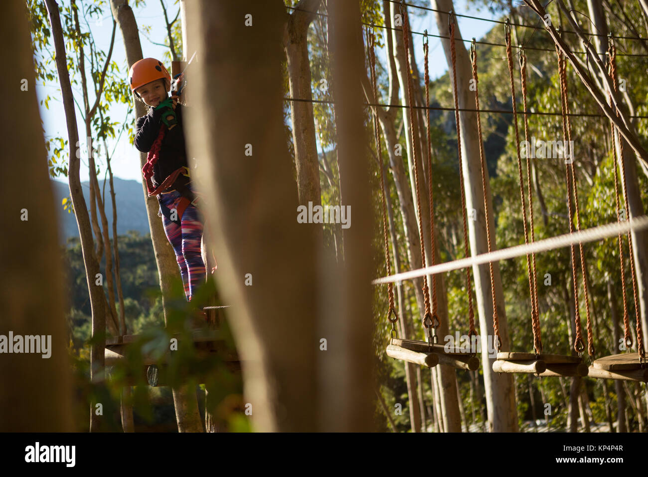 Little girl wearing helmet crossing zip line in the forest Stock Photo ...