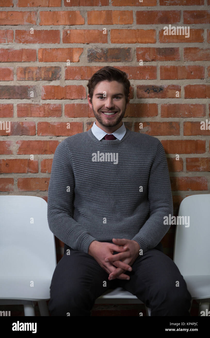 Smiling executive sitting on chair in waiting area of office Stock ...