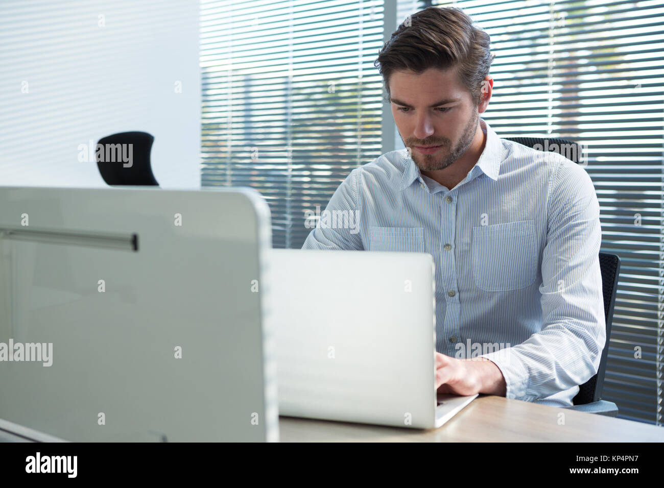 Young executive man using his laptop in the office Stock Photo - Alamy