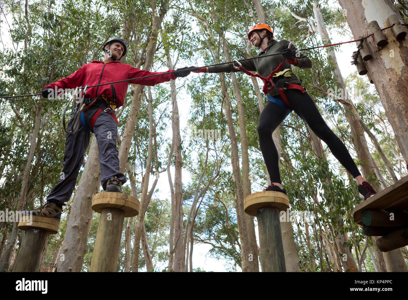 Hiker couple helping each other to cross obstacles in the forest during ...