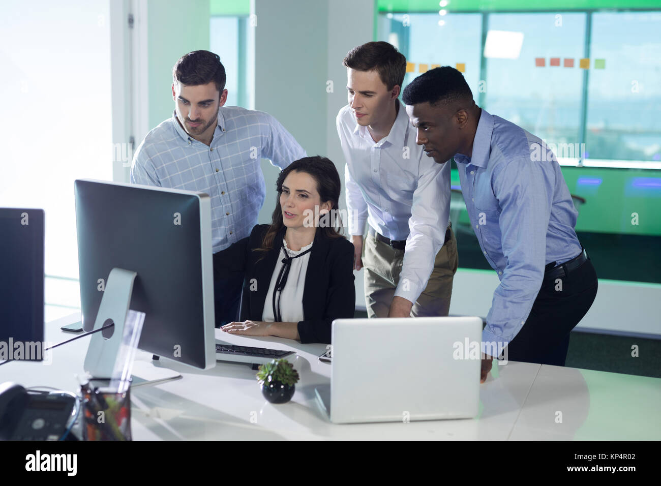 Executives discussing over personal computer in office Stock Photo - Alamy