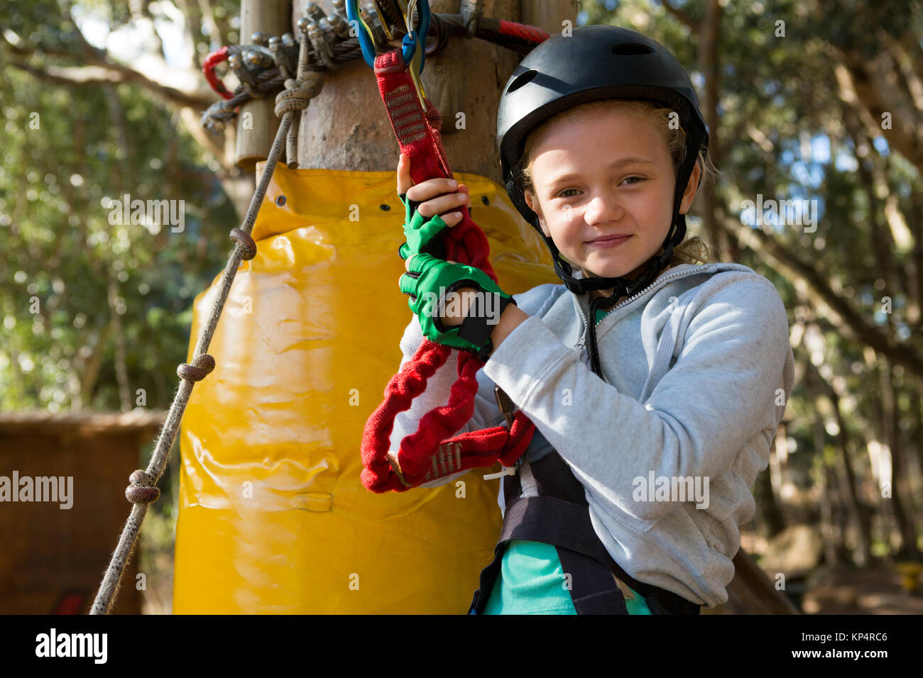 Little girl wearing helmet getting ready to ride zip line in the forest ...