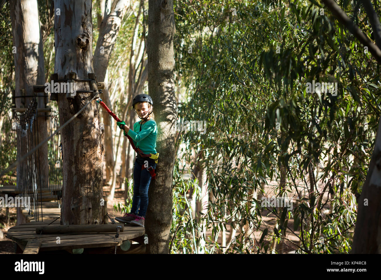 Little girl wearing helmet ready to ride zip line in the forest Stock ...