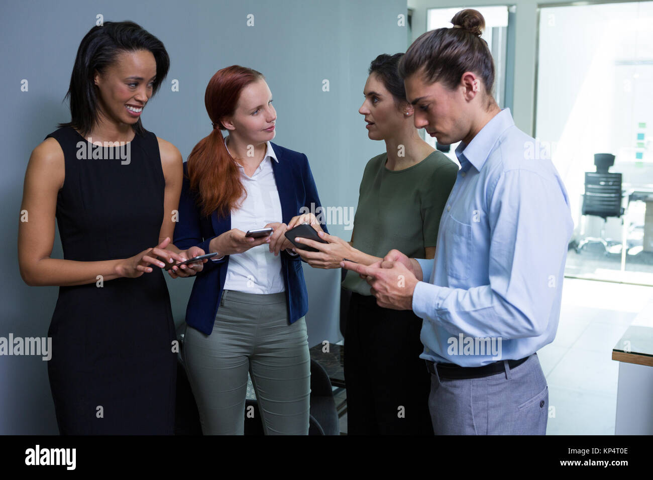 Smiling executives using mobile phone in the office Stock Photo - Alamy