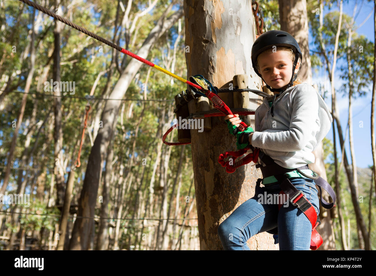 Little girl wearing helmet getting ready to ride zip line in the forest ...