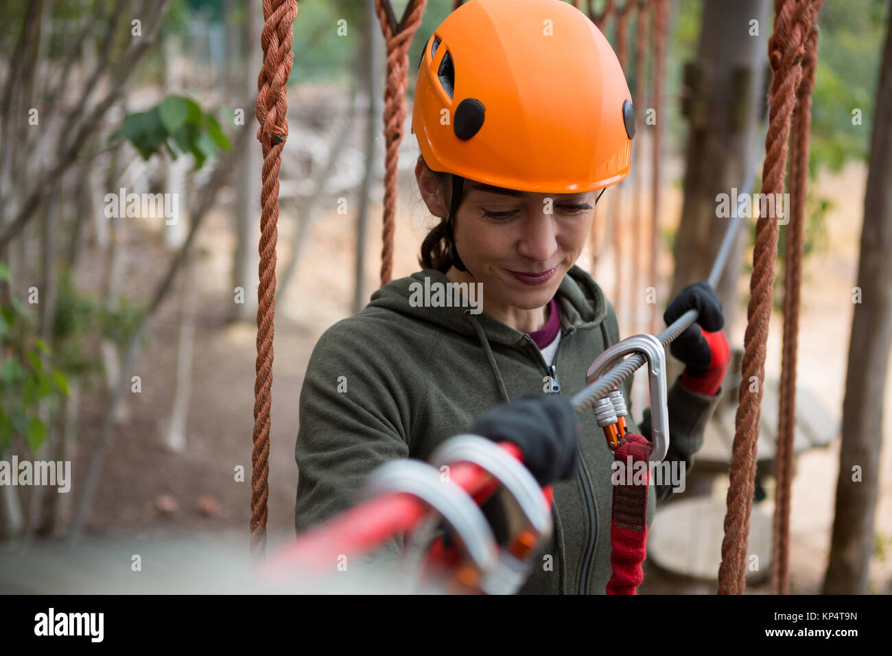 Young smiling woman holding zip line cable in the forest during daytime ...