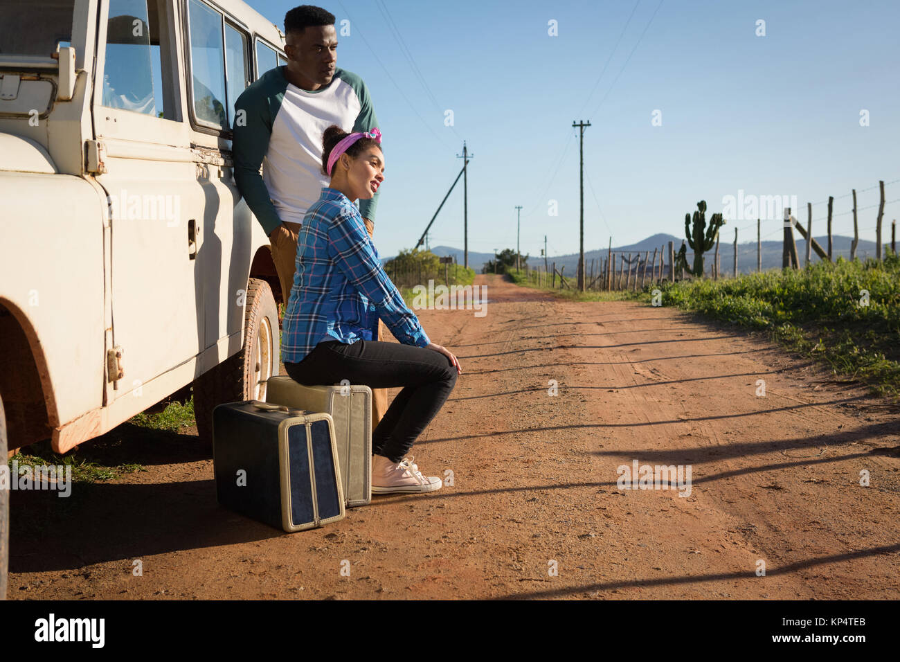 Young couple sitting on suitcase at countryside Stock Photo - Alamy