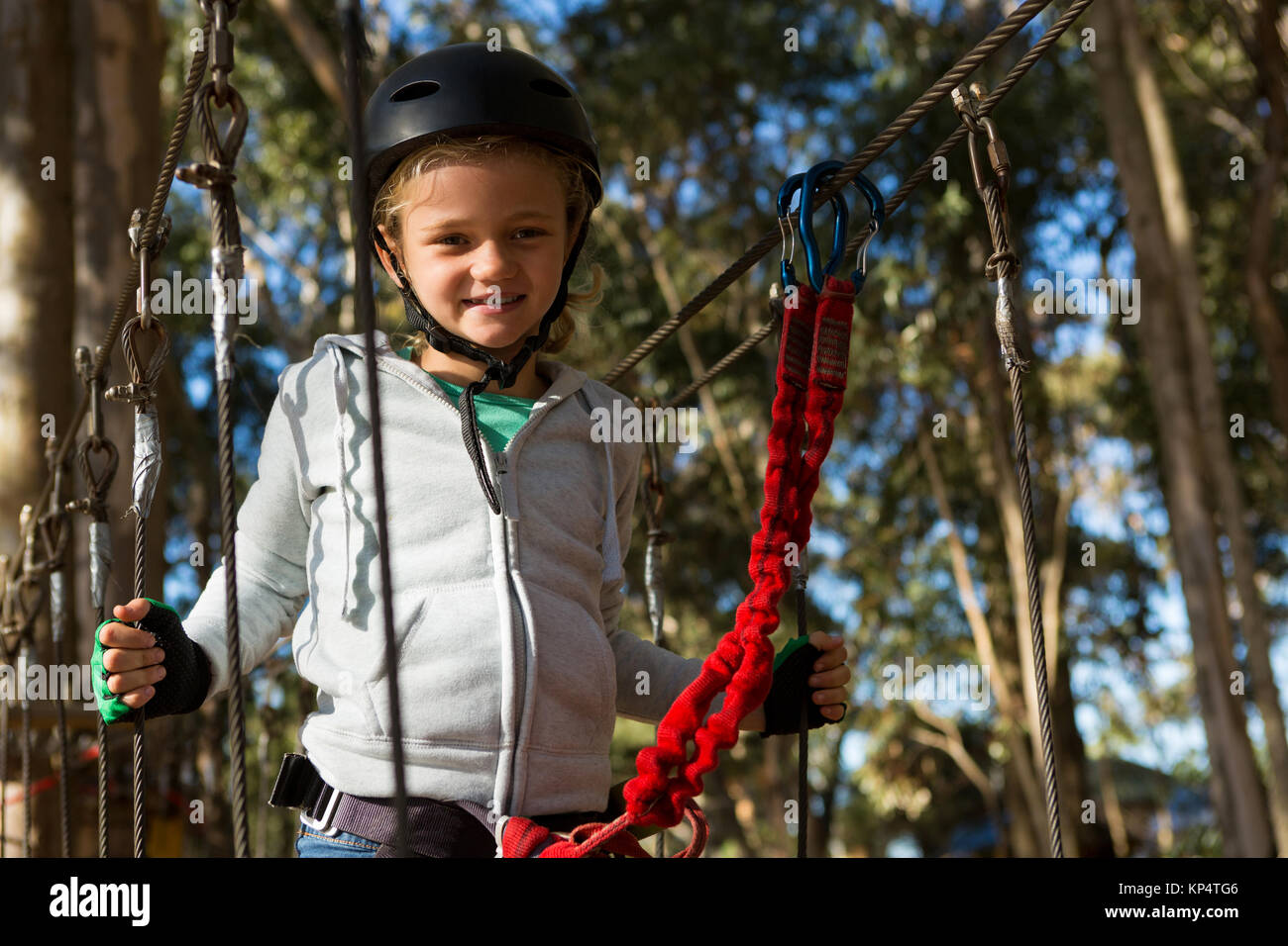 Little girl wearing helmet standing near zip line in the forest Stock ...