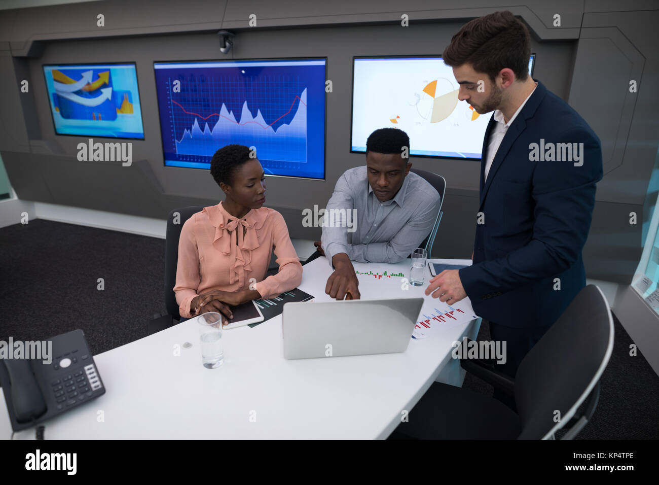 Male and female executives discussing over graph in boardroom Stock ...