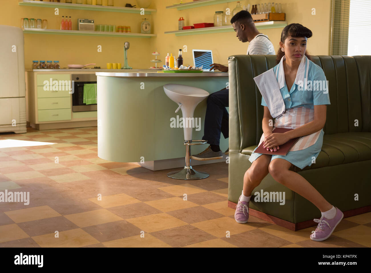 Waitress holding menu card while man using laptop in restaurant Stock ...