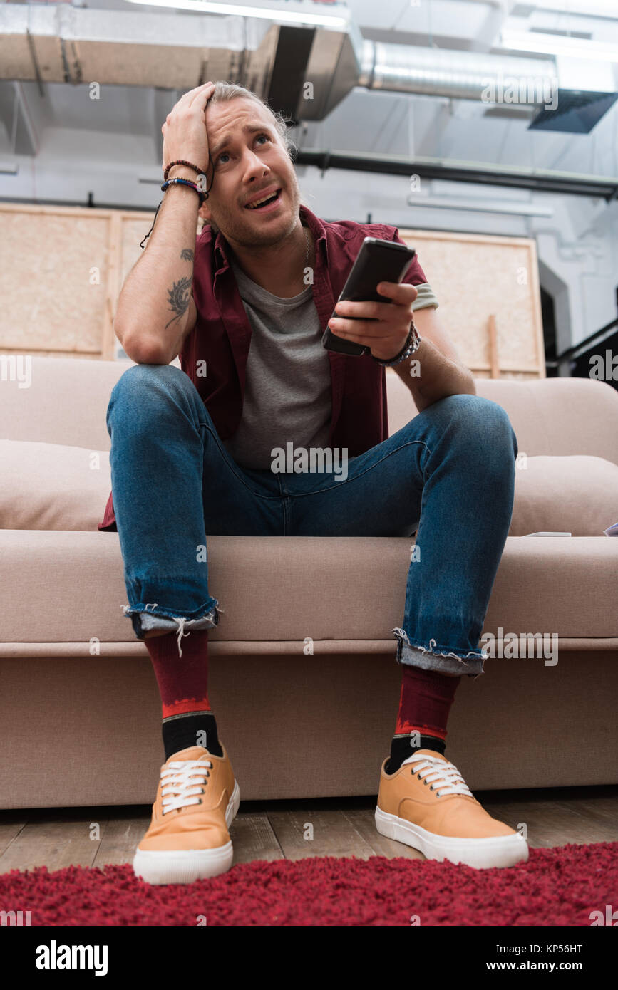 upset handsome man with remote control watching tv at home Stock Photo ...