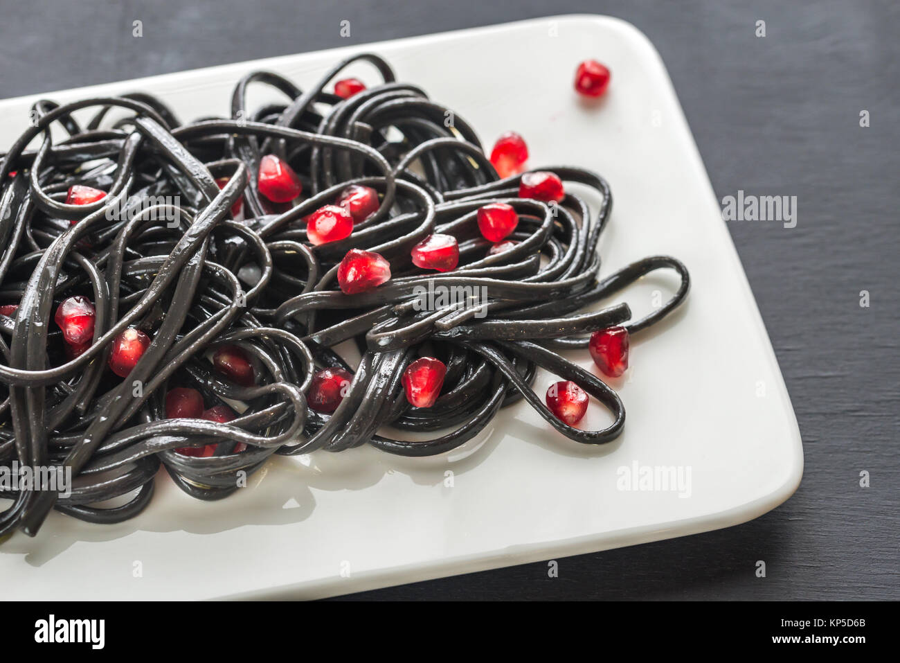 Black pasta with pomegranate seeds Stock Photo - Alamy