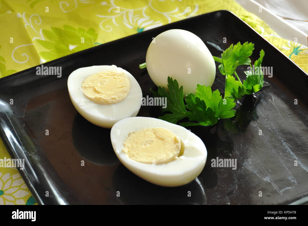 Boiled eggs and a parsley sprig on a black baking tray. Process of ...