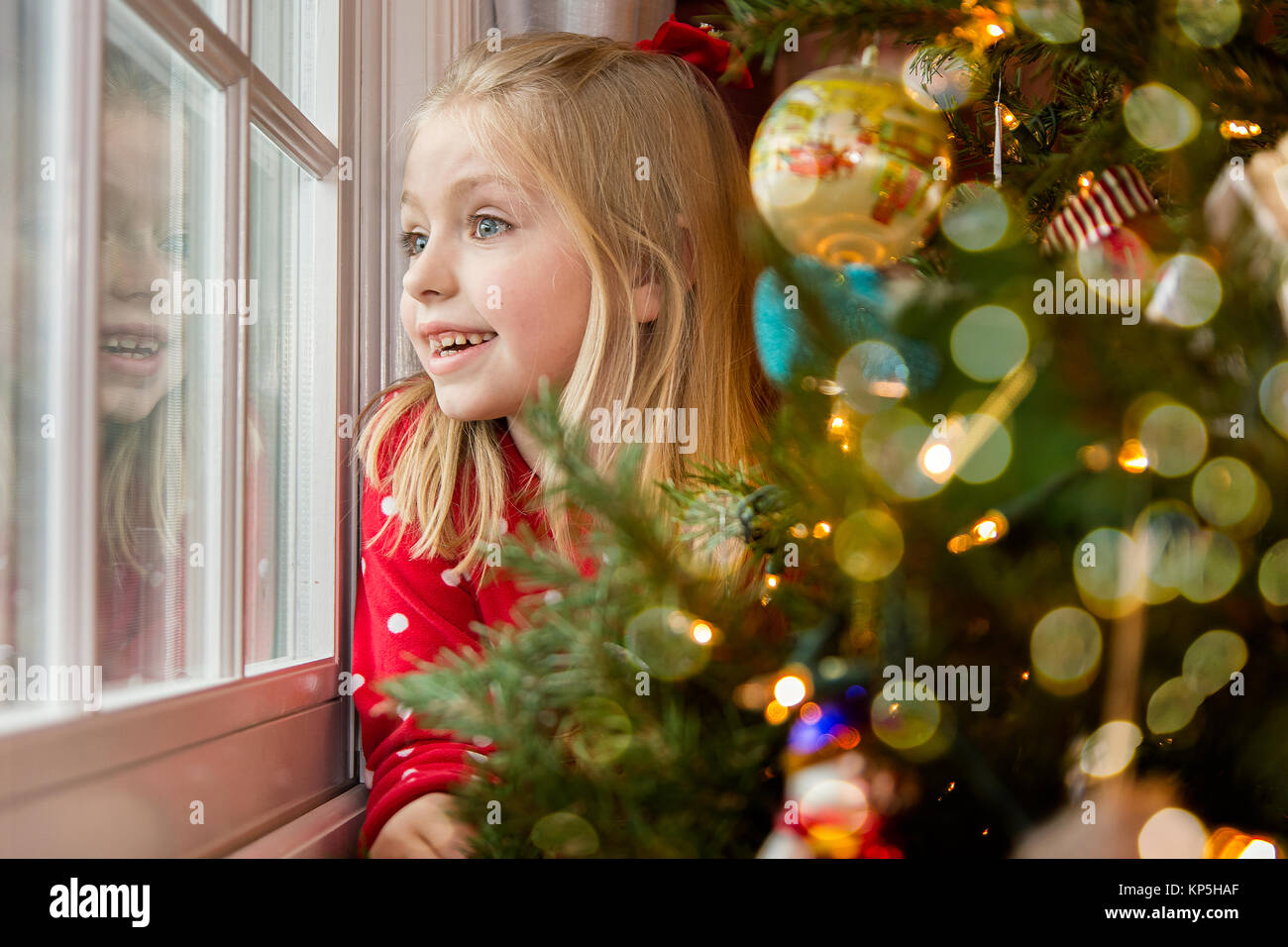 adorable beautiful young school age girl looking out window waiting for ...