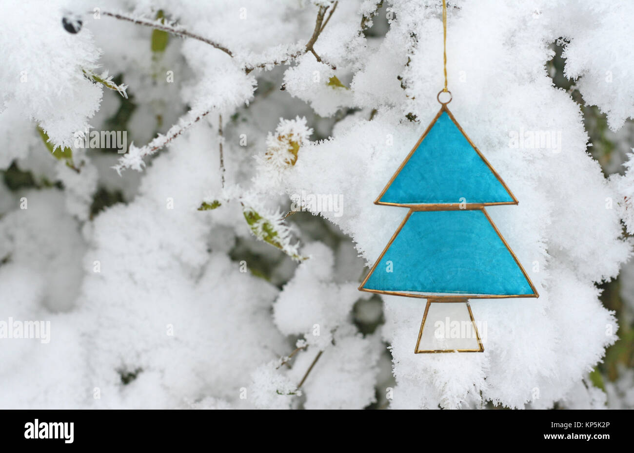 blue Christmas pendant in tree shape nagning on a bush covered with ...