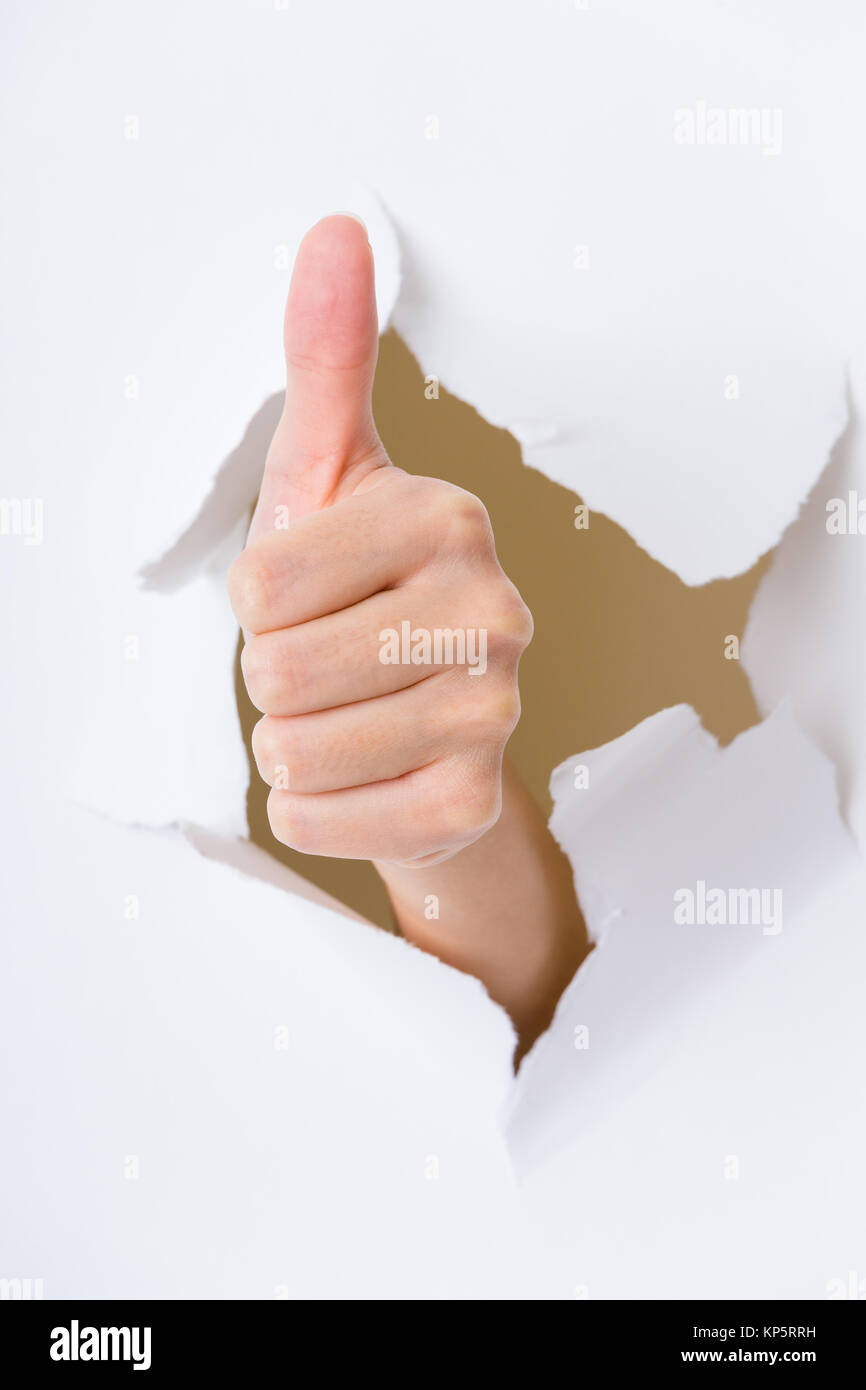 Thumb up hand gesture through a hole in paper Stock Photo - Alamy