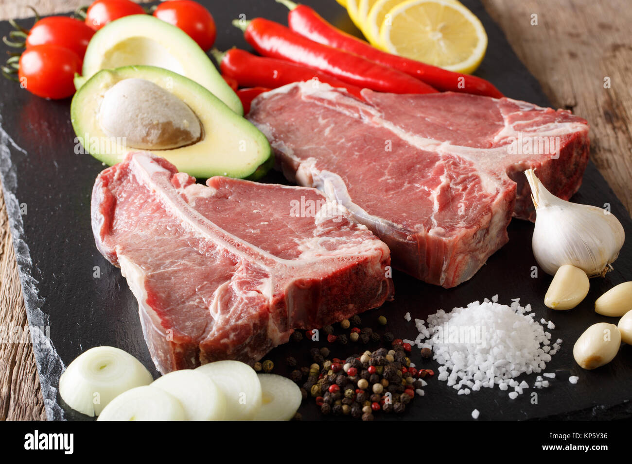 Raw t-bone steak with ingredients close-up on the table. horizontal ...