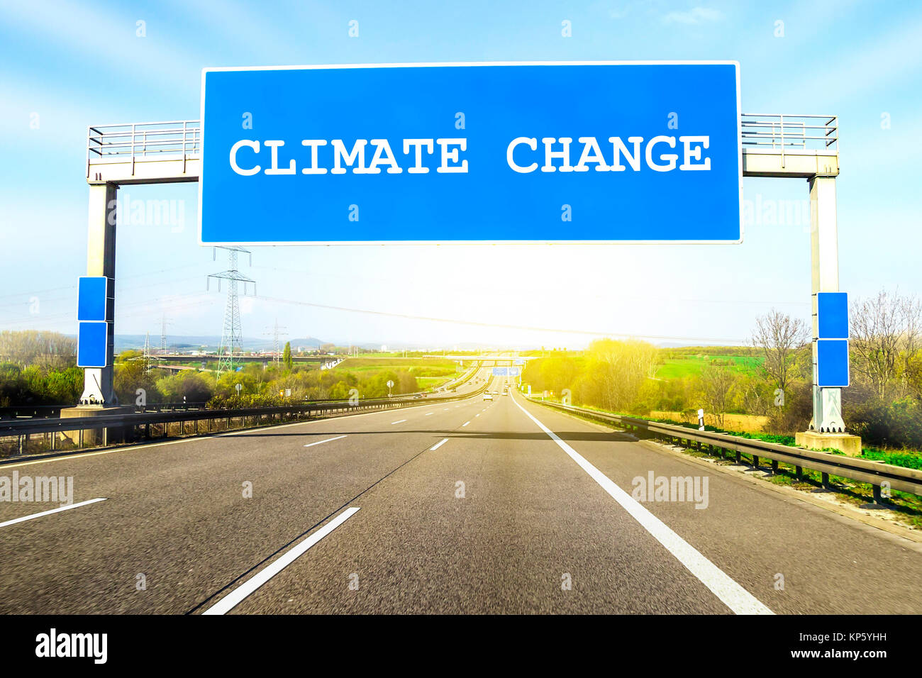 Blue freeway sign over the road on sunny day with words Climate Change ...