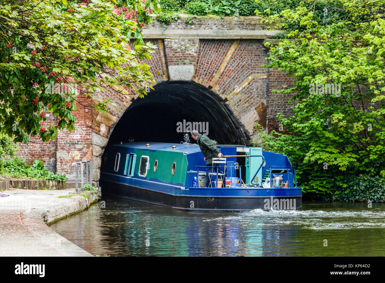One man at the tiller of a blue narrowboat negotiating the Islington ...