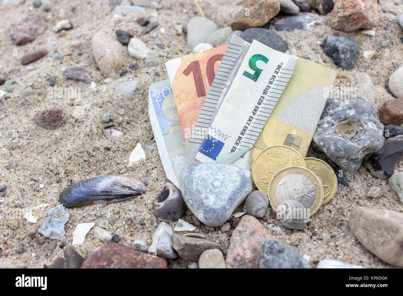 coins,bills,stones and shells in the sand Stock Photo - Alamy