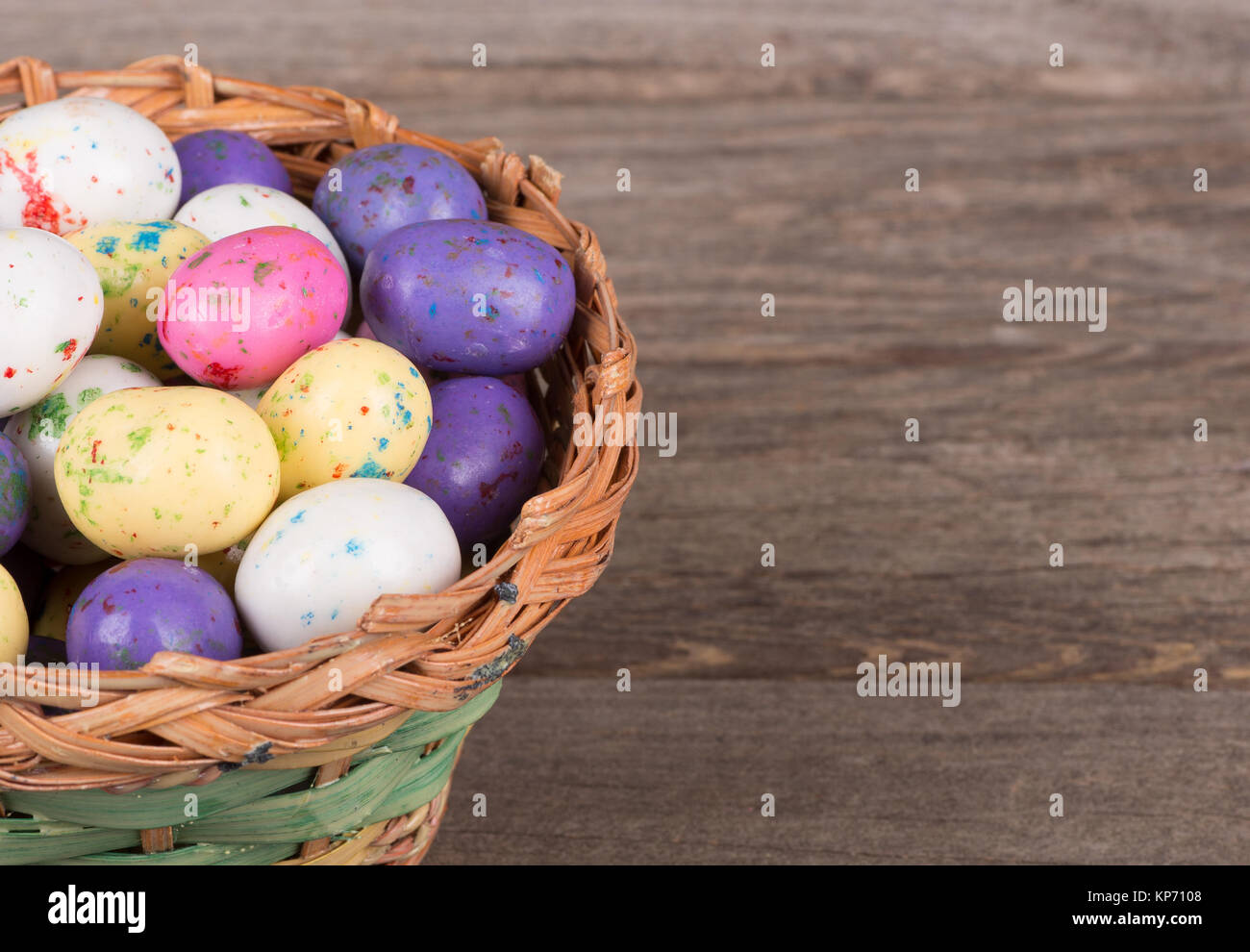 Closeup of colorful Easter egg candy in a basket on a wood surface ...