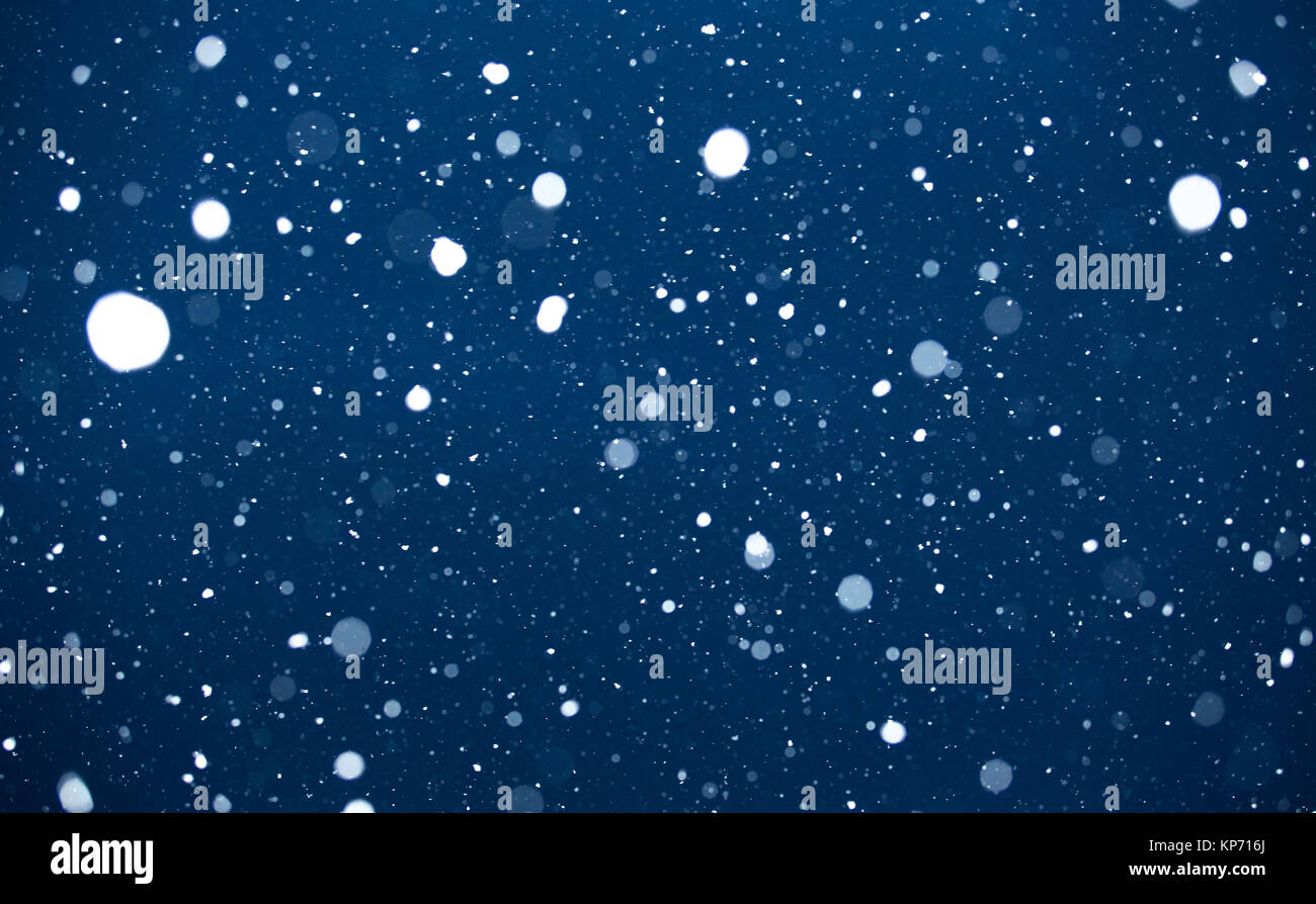 Falling snow on blue background Stock Photo - Alamy