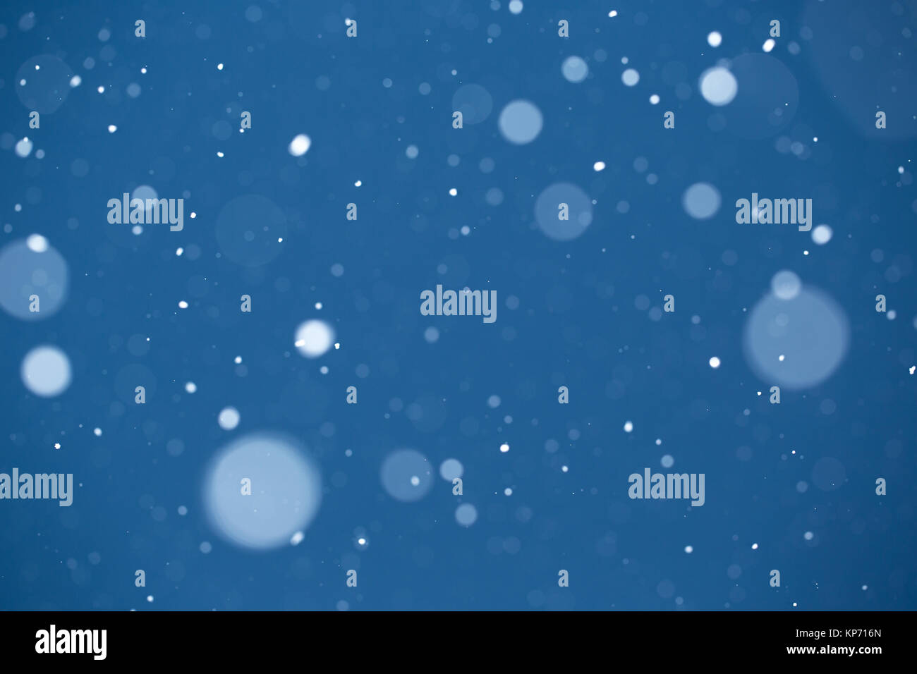Falling snow on blue background Stock Photo - Alamy