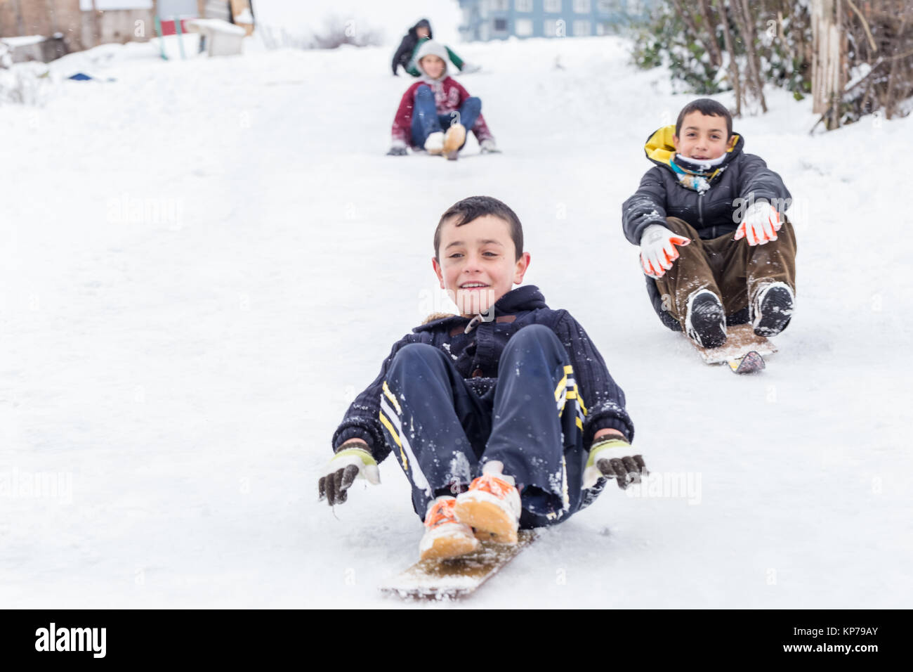 Children slide on snow in old school style with hardwood sled in ...