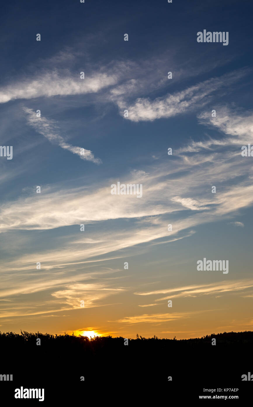 Vertical cloudscape of layered clouds at sunset with Sun taken at ...