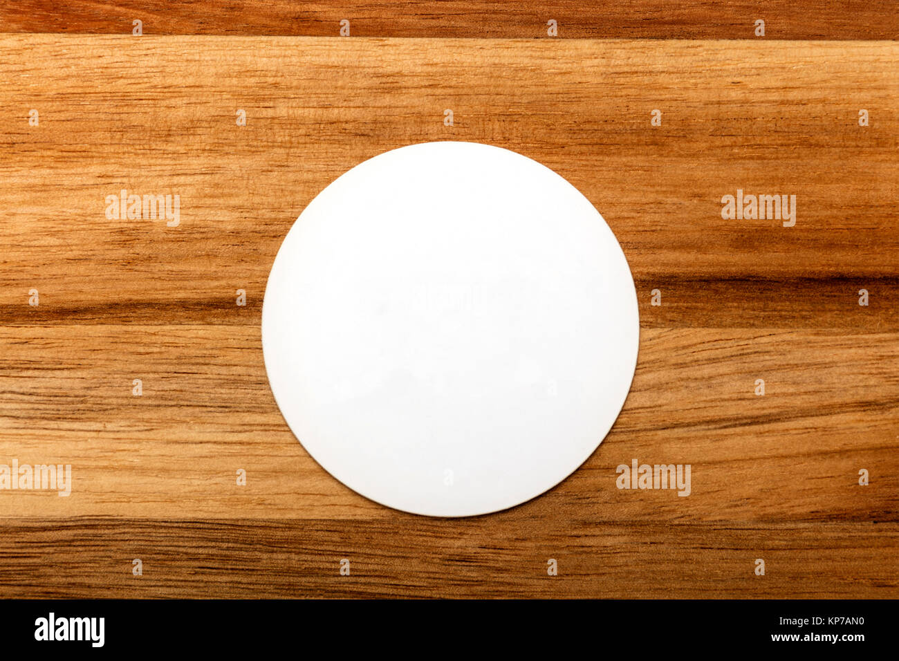 A photo of a round white business card on a rustic wooden texture. A ...