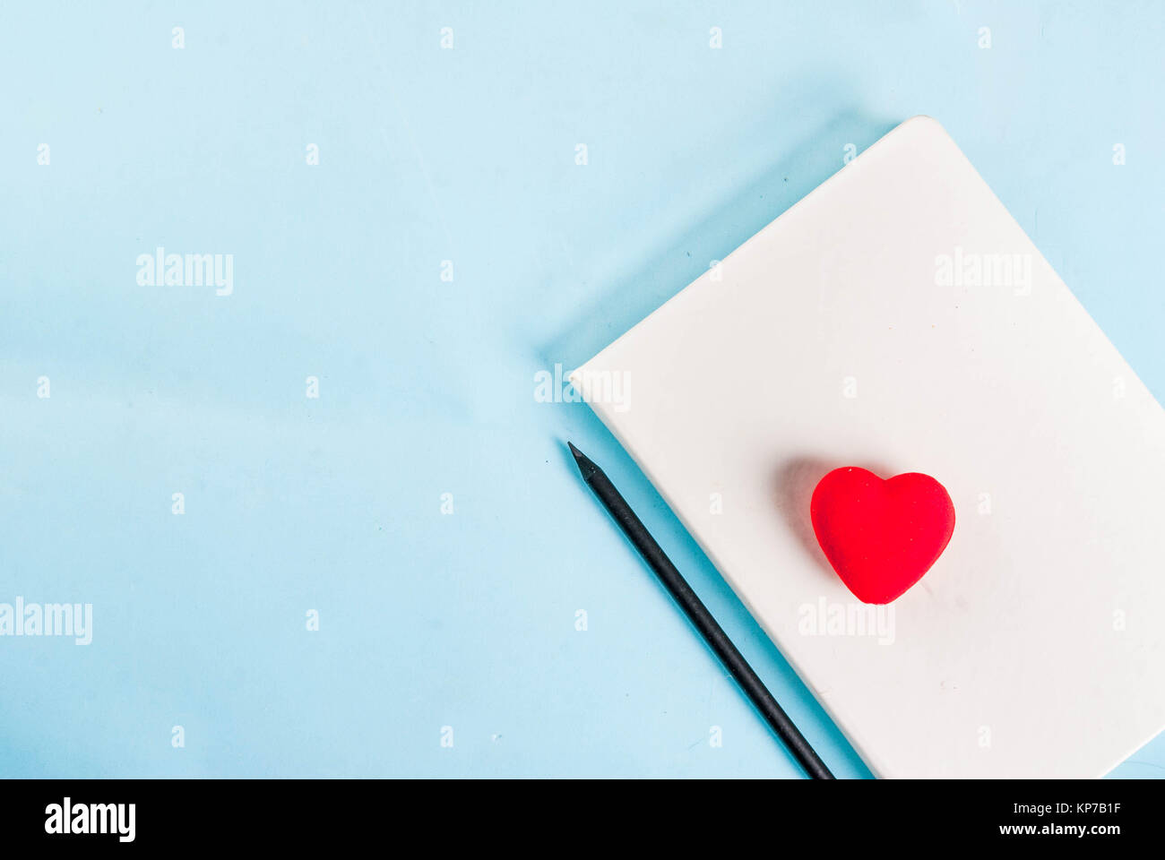 Valentine's day light blue background. Red heart, notepad and pencil ...