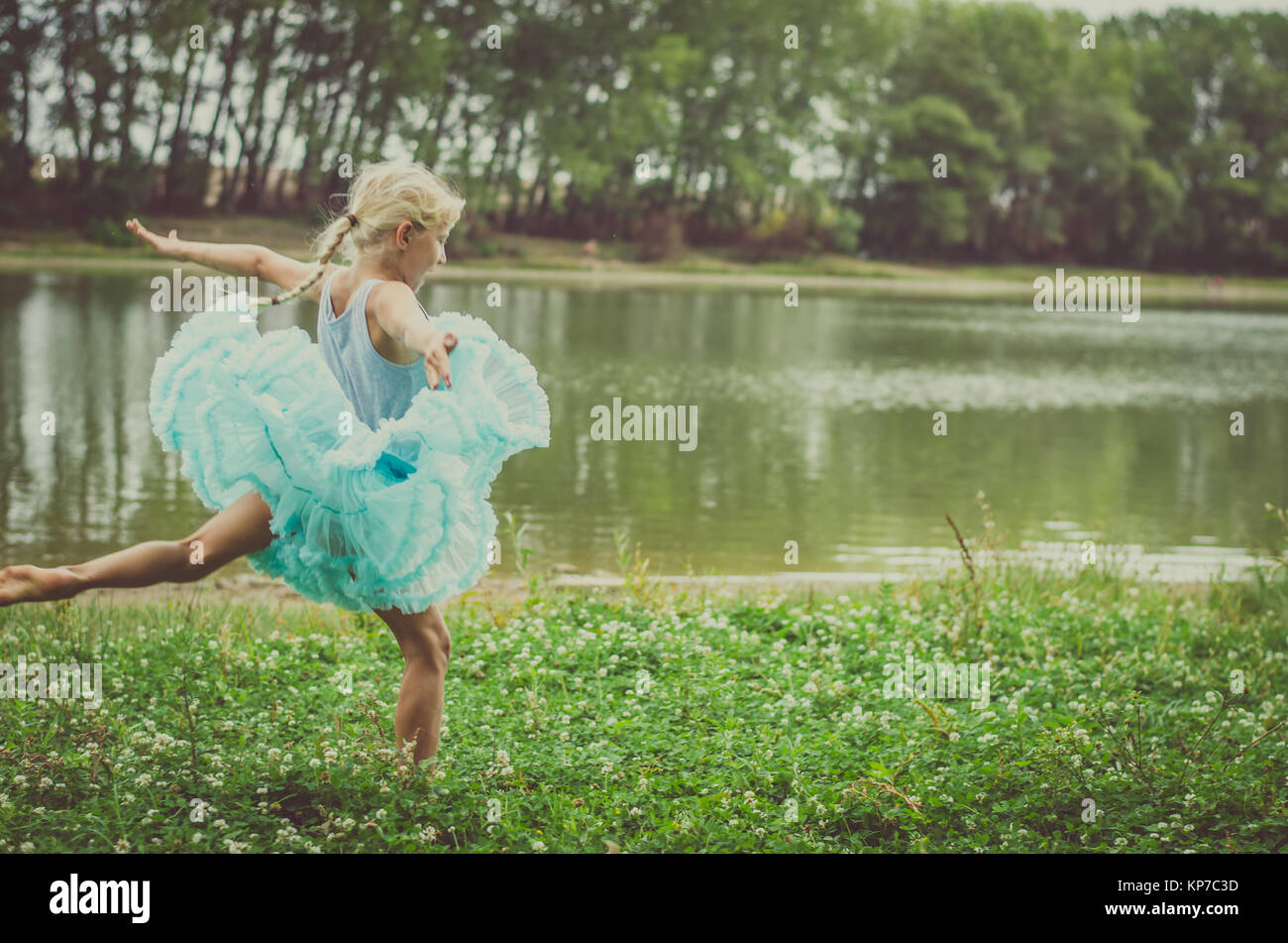 little child in blue dress dancing free in the green nature in the ...
