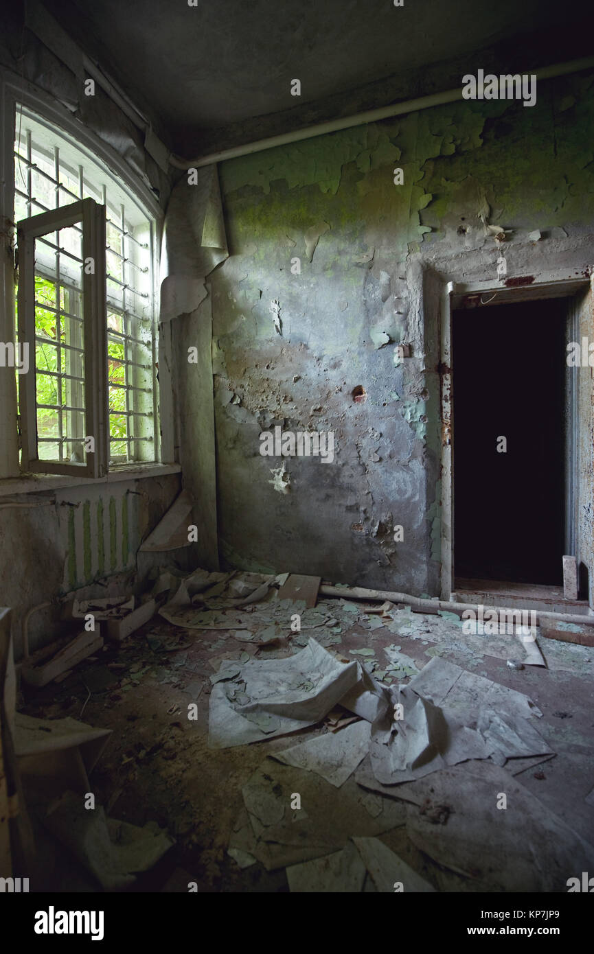 Destroyed room in Pripyat, open windows with bars, black door opening ...