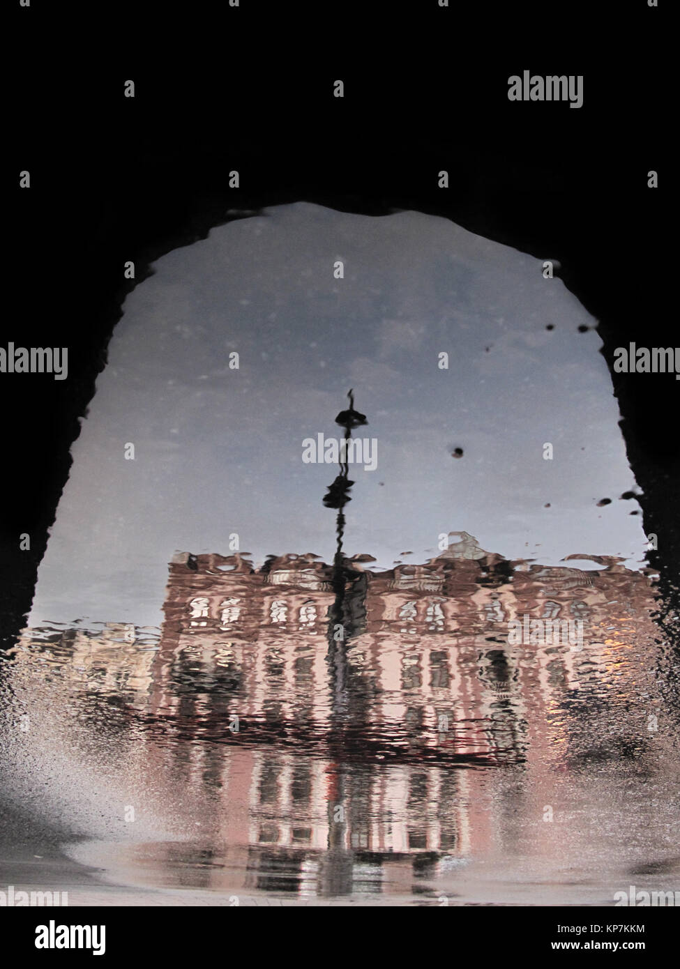 Reflection in the puddle is a black arc arch, behind the arch is a ...