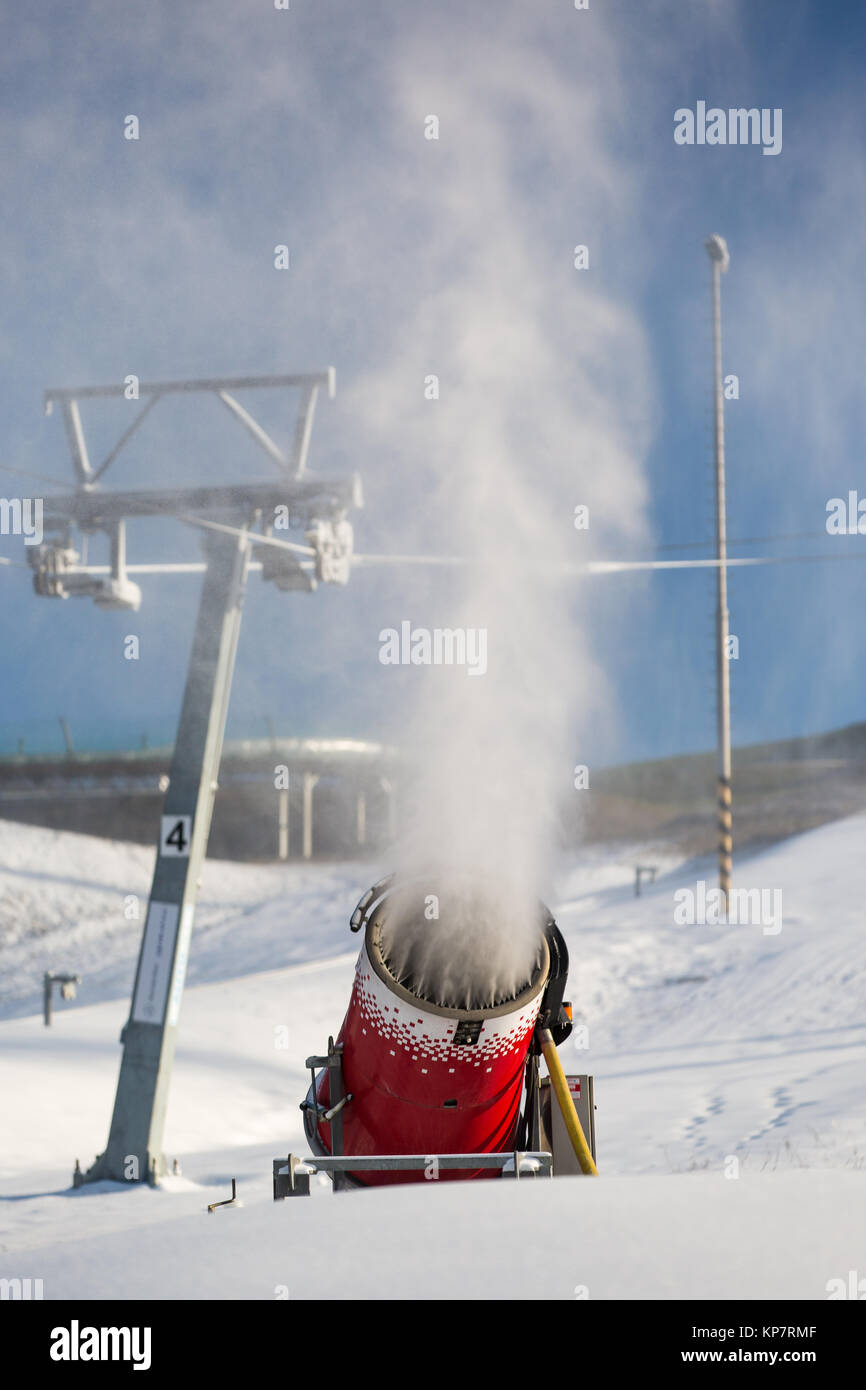 Snow-machine bursting artificial snow over a skiing slope to alow for ...