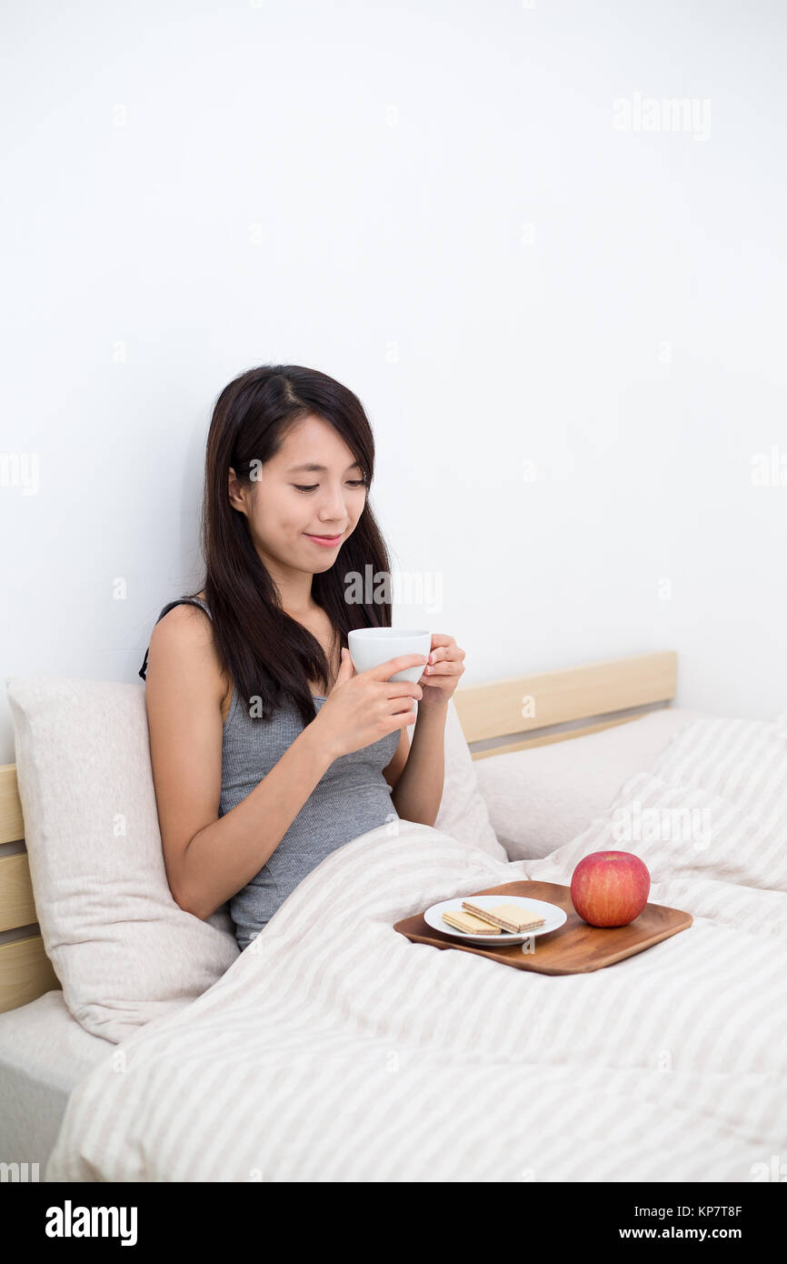 Woman having the breakfast and sitting on the bed Stock Photo - Alamy